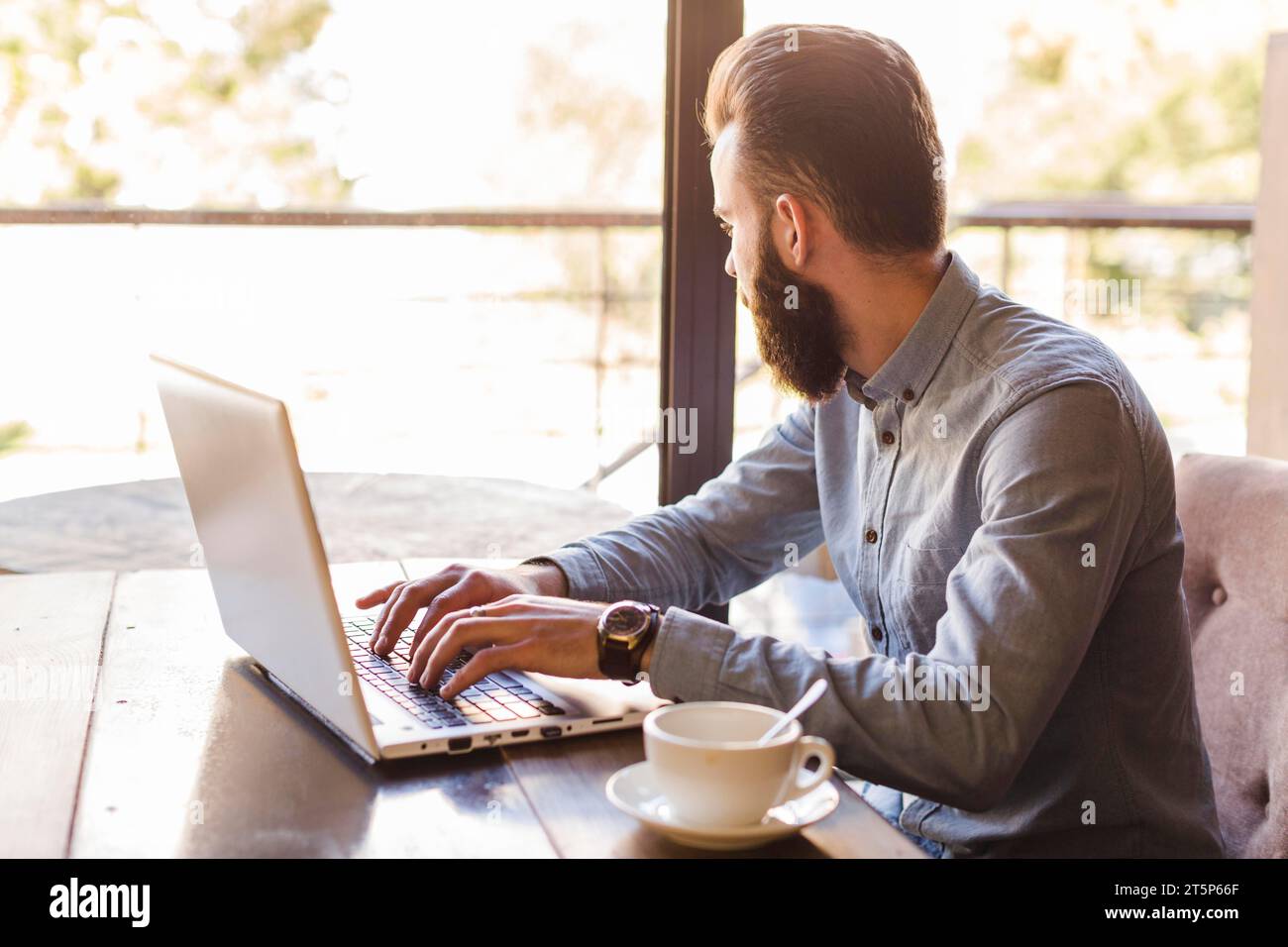 Side view man typing laptop keypad with cup coffee desk Stock Photo - Alamy