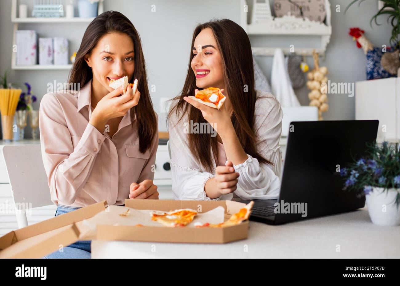 Smiley women eating pizza after working Stock Photo - Alamy