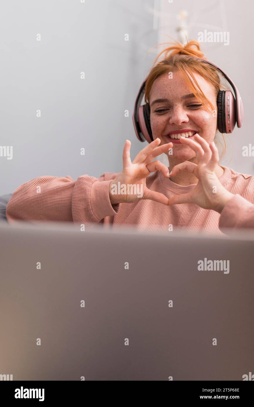 Smiley female teacher showing heart sign students during online class ...