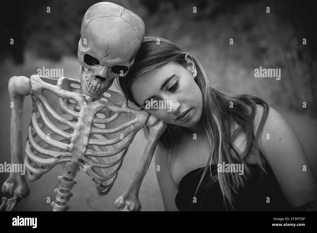 Young woman sitting road with skeleton looking down Stock Photo - Alamy