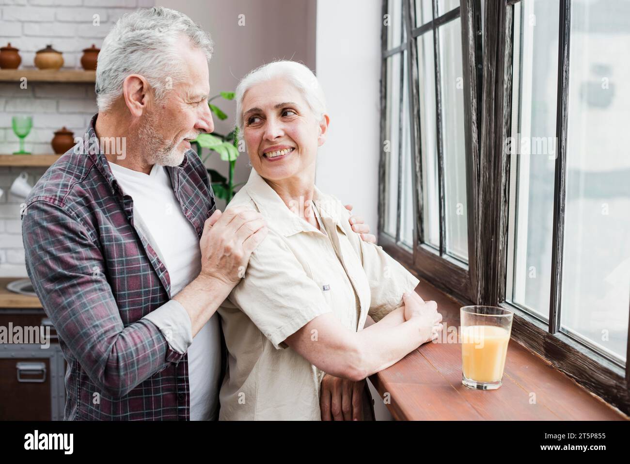 Elder couple looking through window Stock Photo - Alamy
