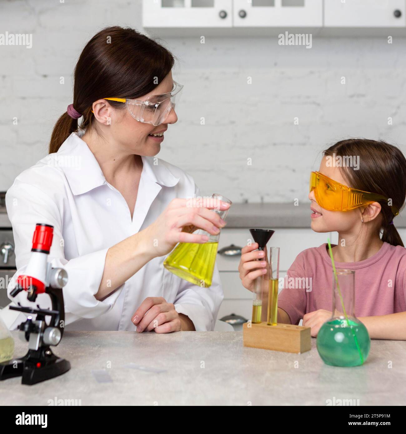 Little girl female teacher doing science experiments with test tubes ...