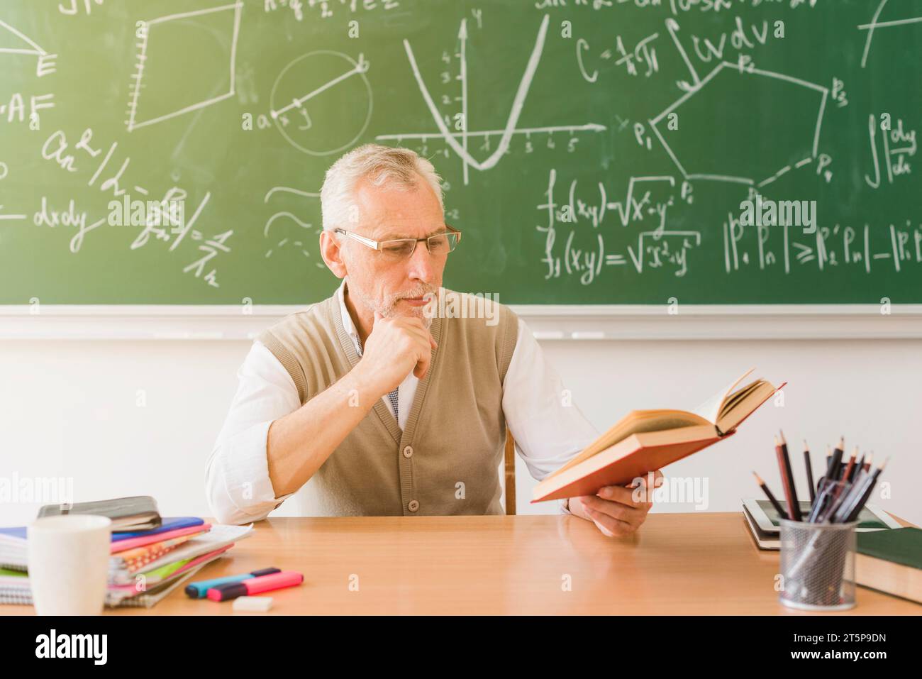 Serious teacher reading book Stock Photo - Alamy