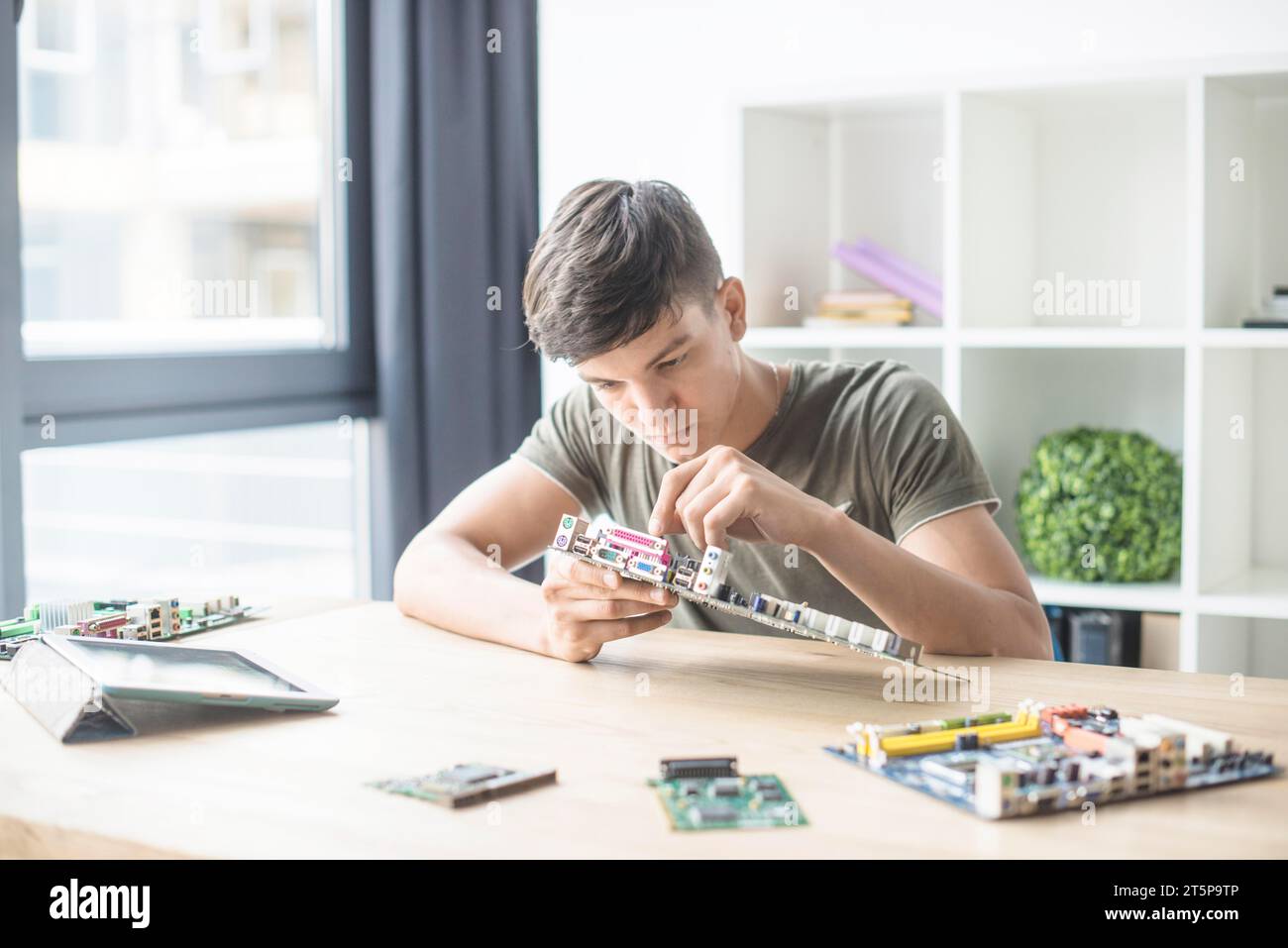 Teenage boy repairing computer motherboard wooden desk Stock Photo - Alamy