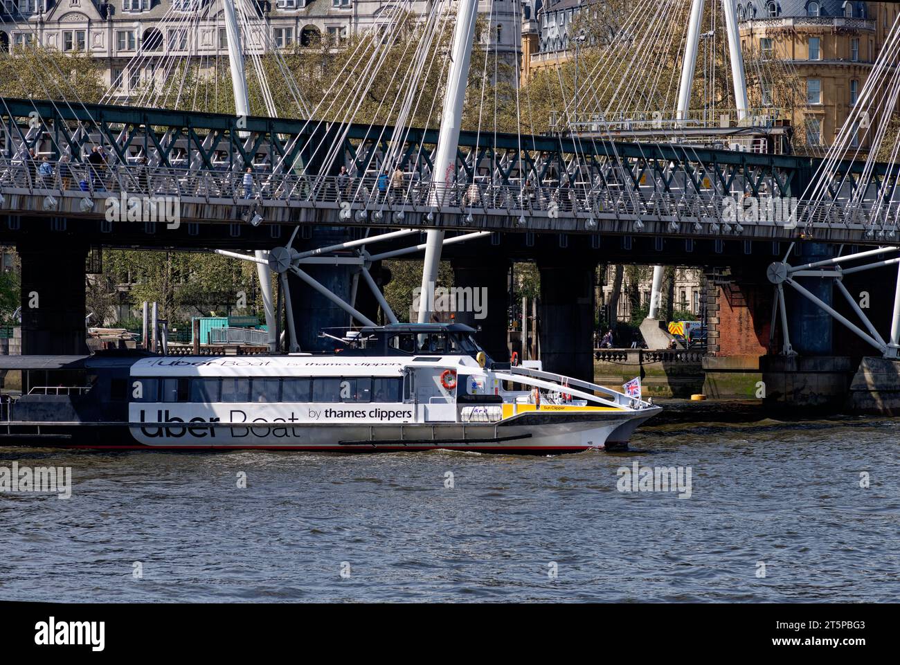 Uber boat passing under the railway Hungerford Bridge and the adjacent ...