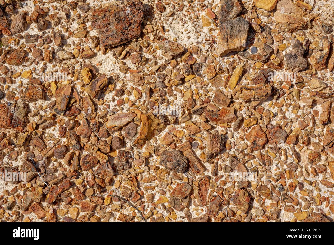 Colorful unusual rocks and stones clustered together on a sandy soil ...