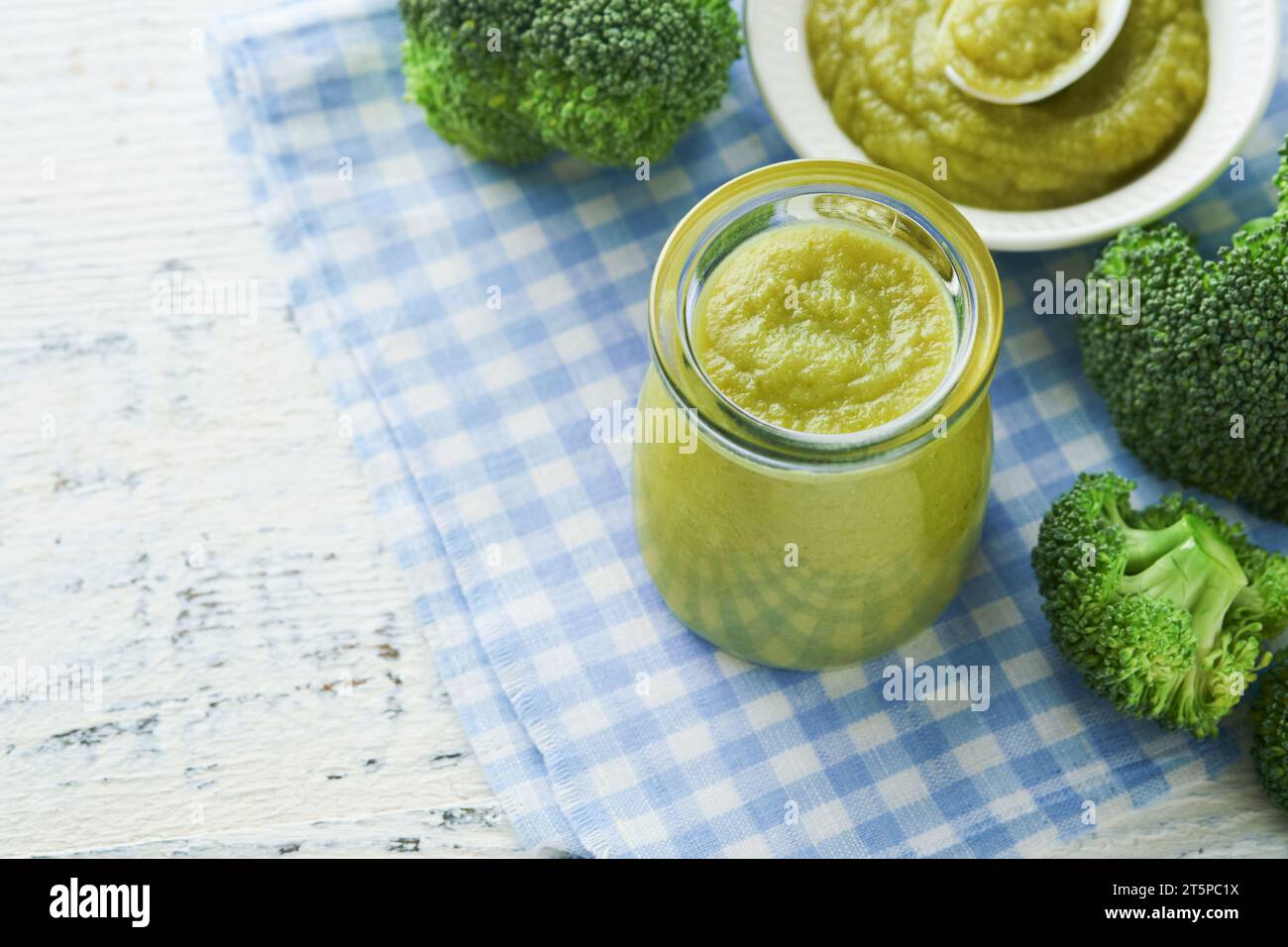 Green broccoli baby food in white bowl and jar on table. Green baby ...