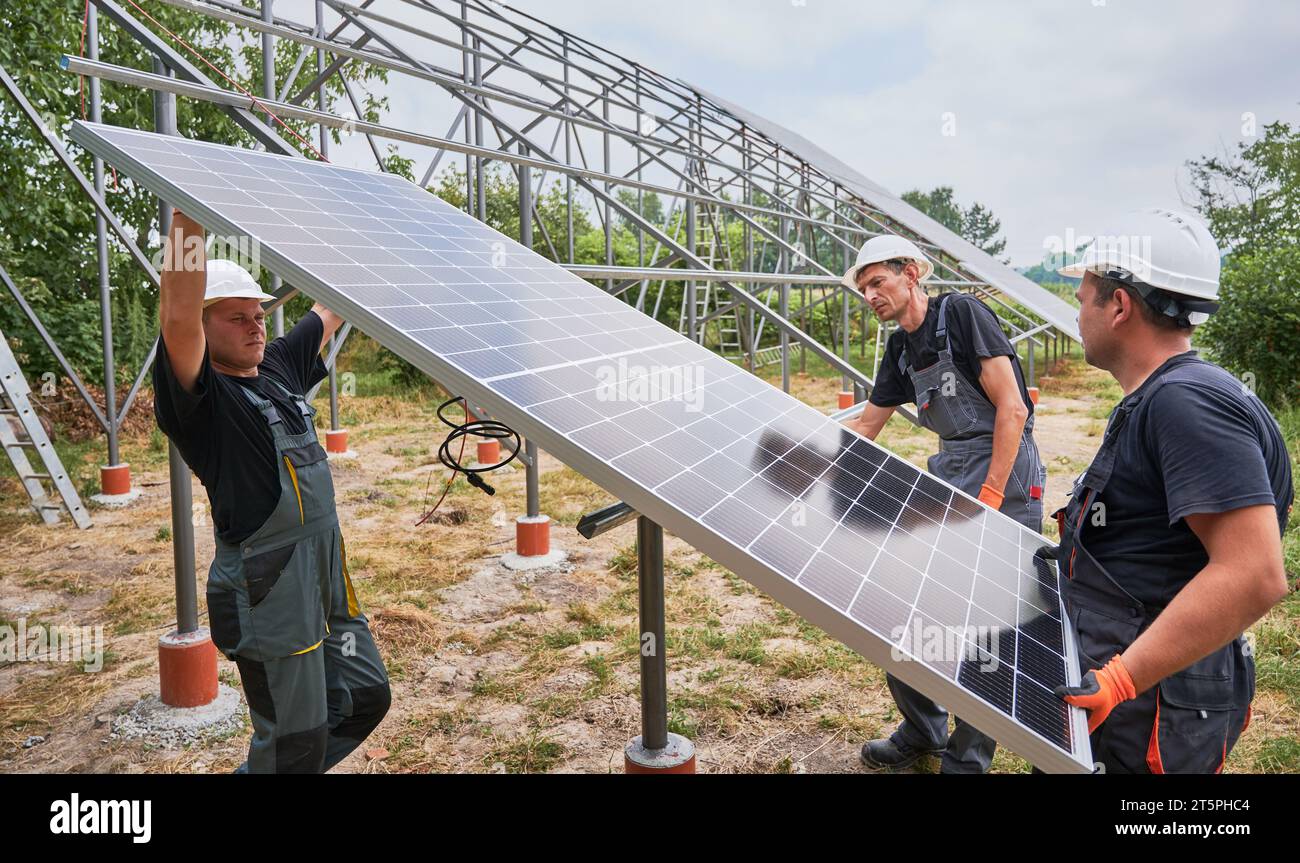Three men solar installers mounting photovoltaic solar panel system ...