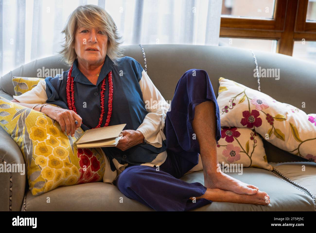 Relaxed mature woman sitting on sofa enjoying leisure time writing in ...