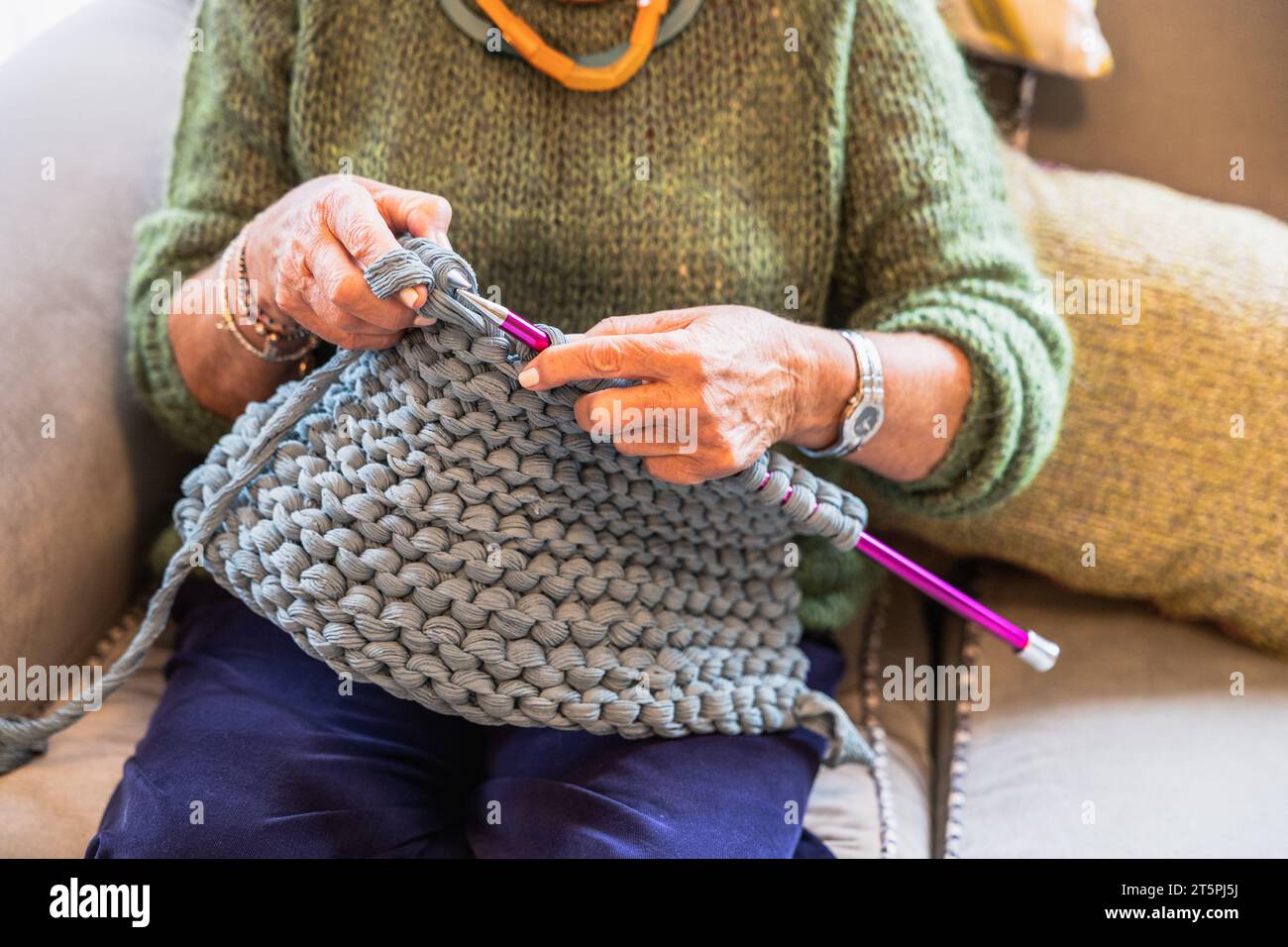 Close-up detail of the wool and needles of the woman's knitting work ...