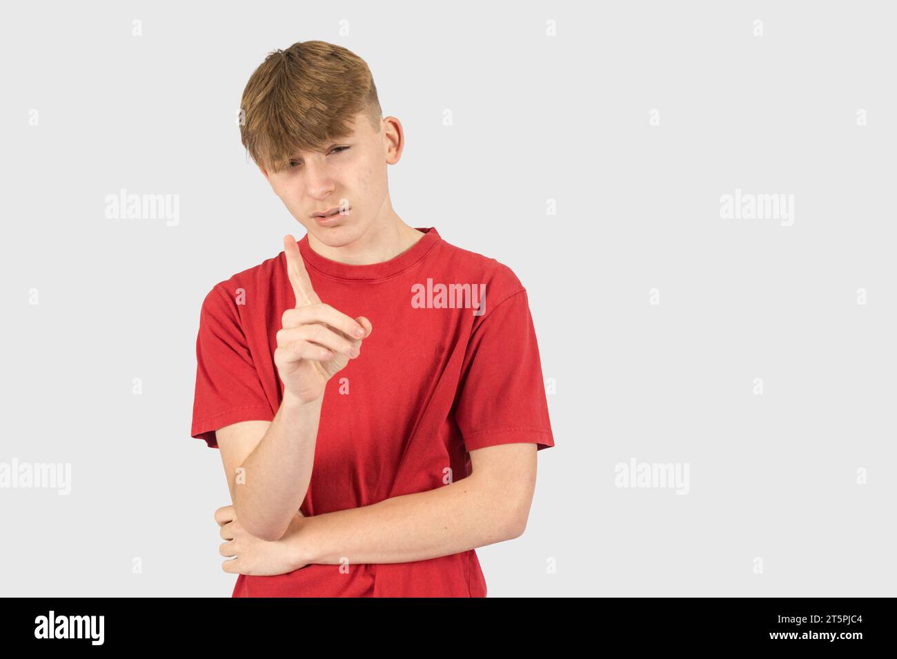 A studio portrait of a unimpressed fifteen year old teenage boy wagging ...