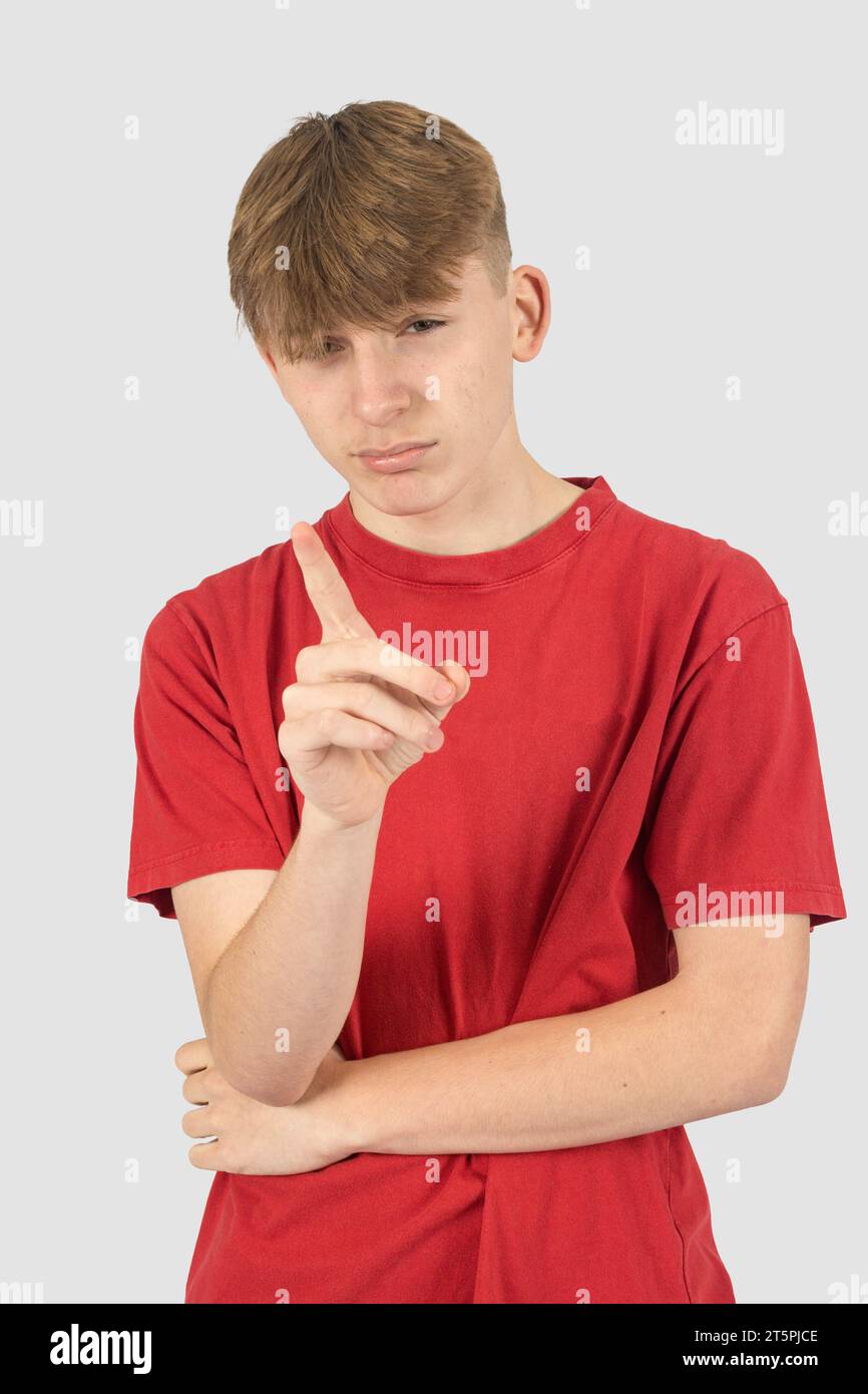 A studio portrait of a unimpressed fifteen year old teenage boy wagging ...