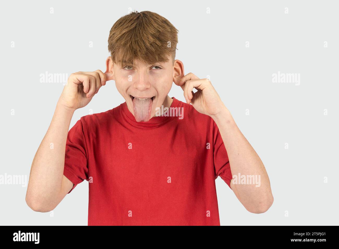 A studio portrait of a goofy fifteen year old teenage boy pulling a ...