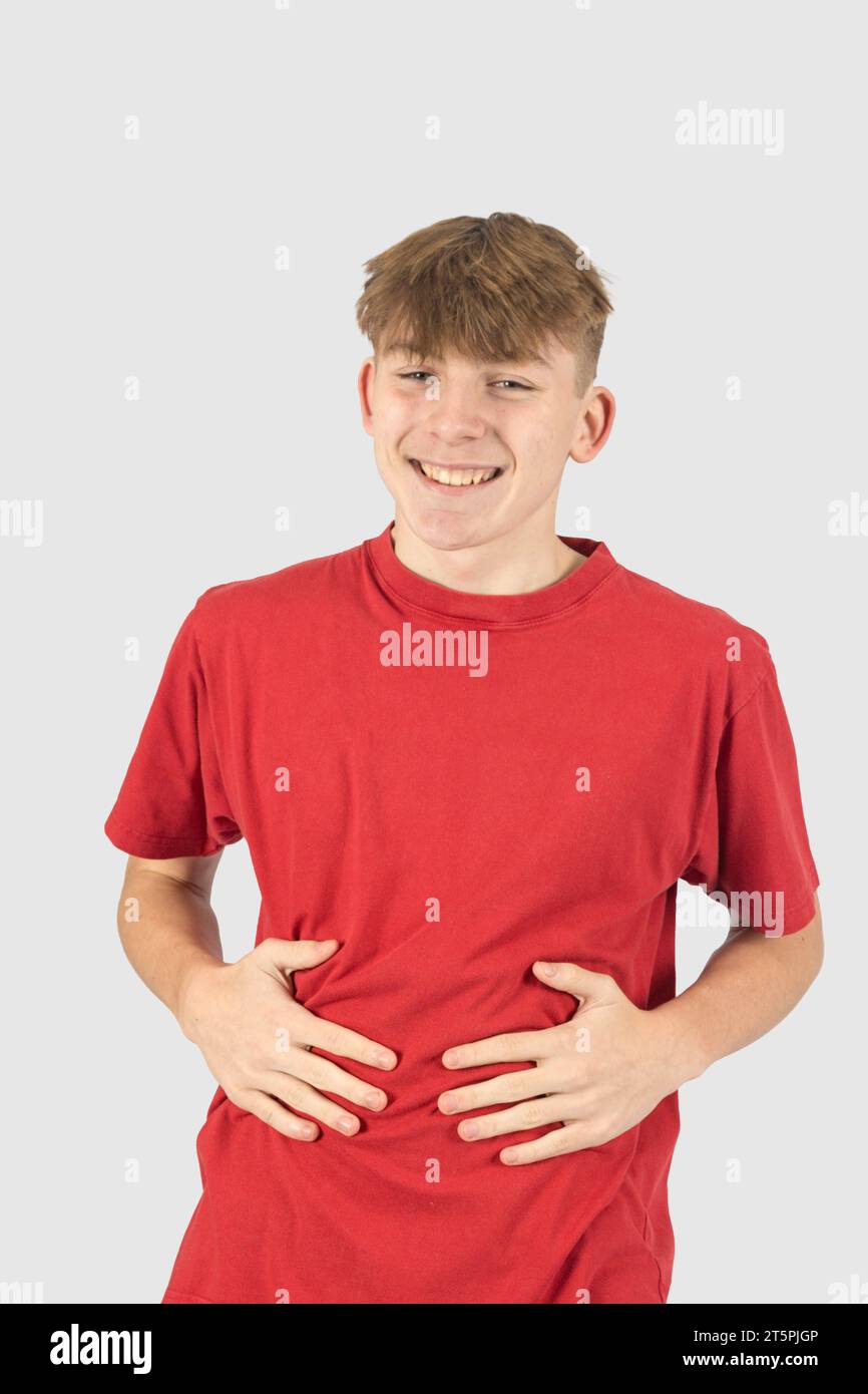 A studio portrait of a pleased fifteen year old teenage boy rubbing his ...