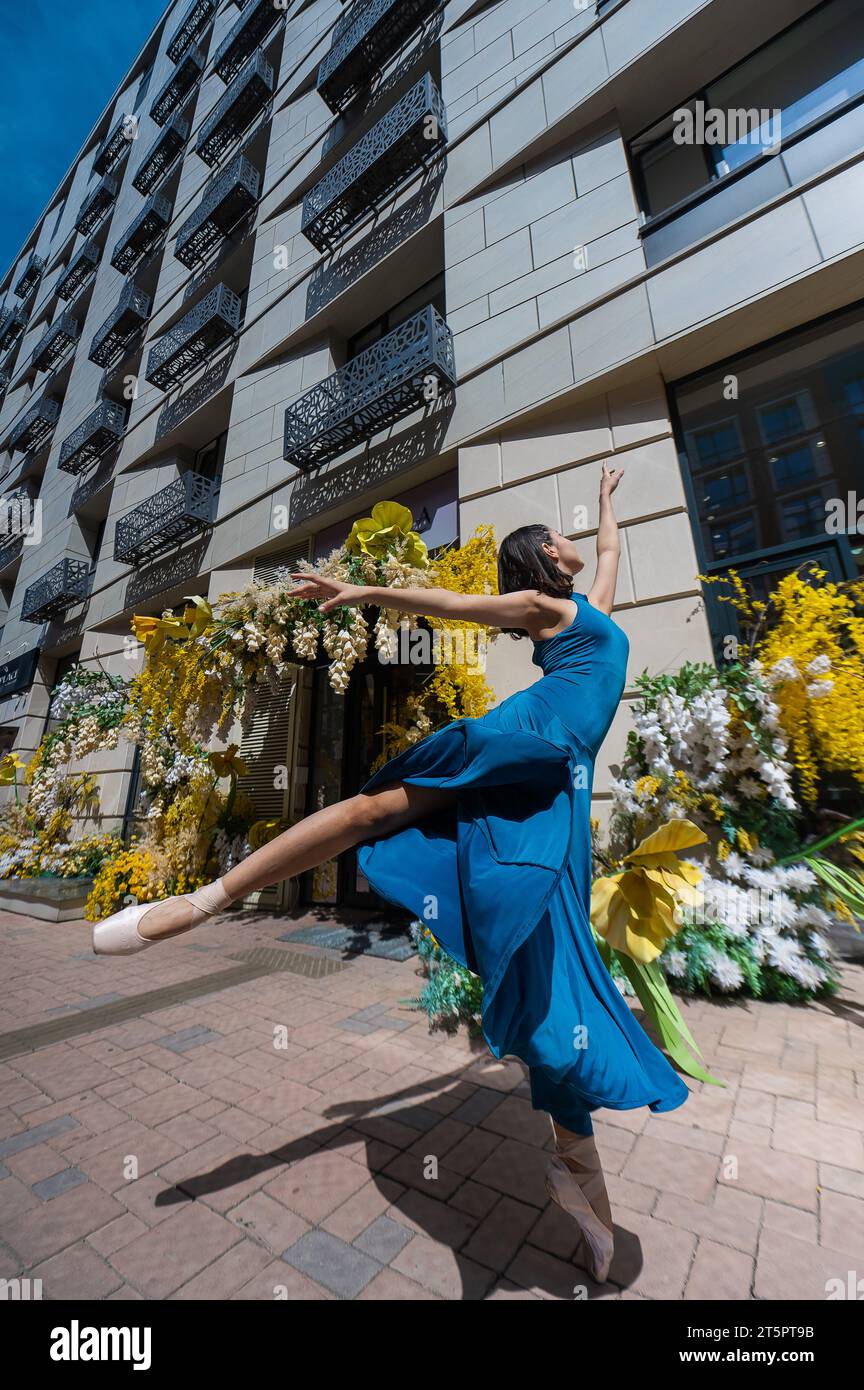 Beautiful Asian ballerina dances against the background of a building ...
