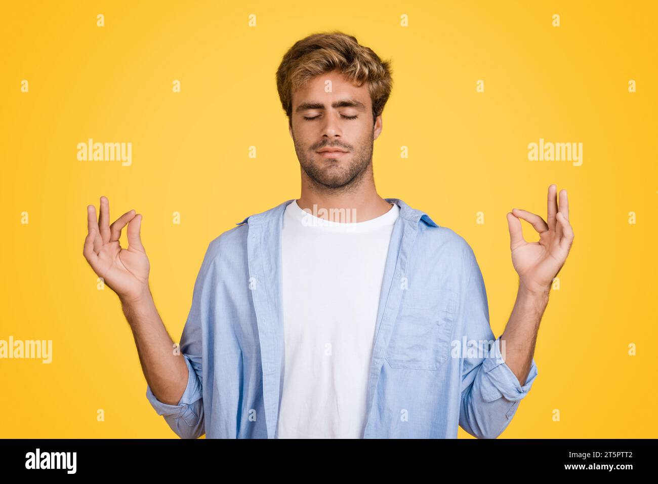 European man meditating, om hand gesture, on yellow background Stock ...