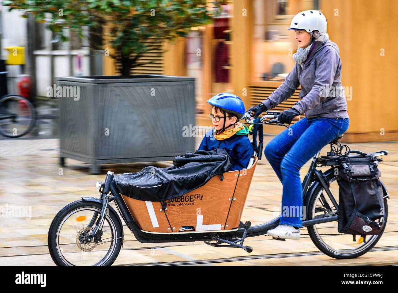 Woman and child cycling along city street in electric power assisted ...