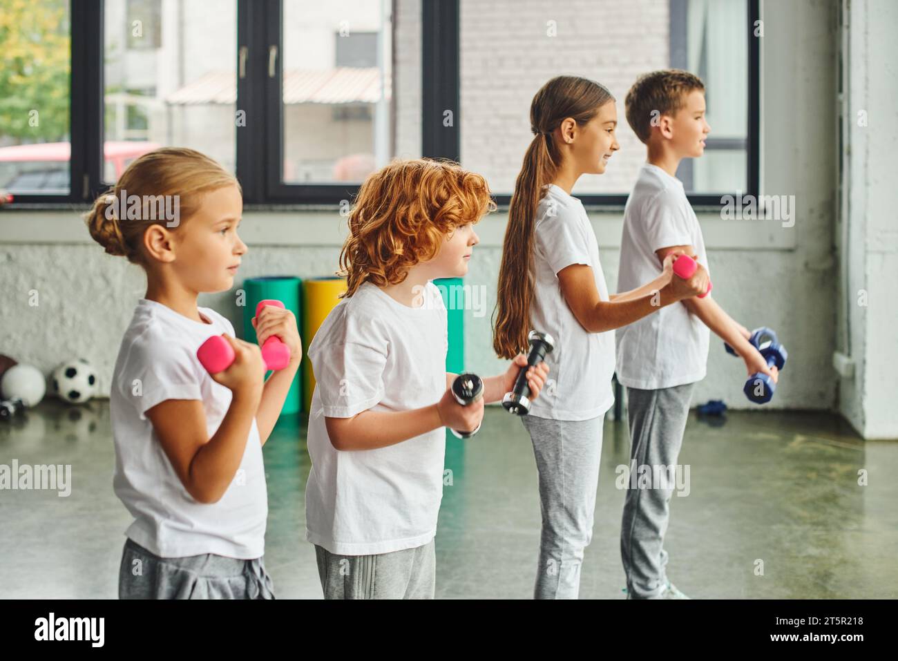 four little pretty children in sportswear posing in profile while ...