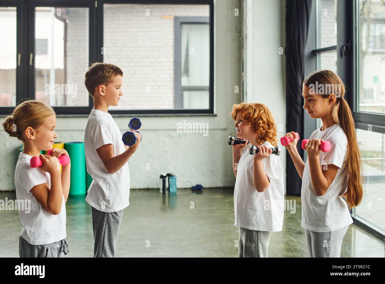 pretty little children standing opposite each other and exercising with ...