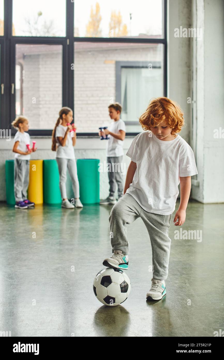 red haired little boy with soccer ball with his pretty friends with ...