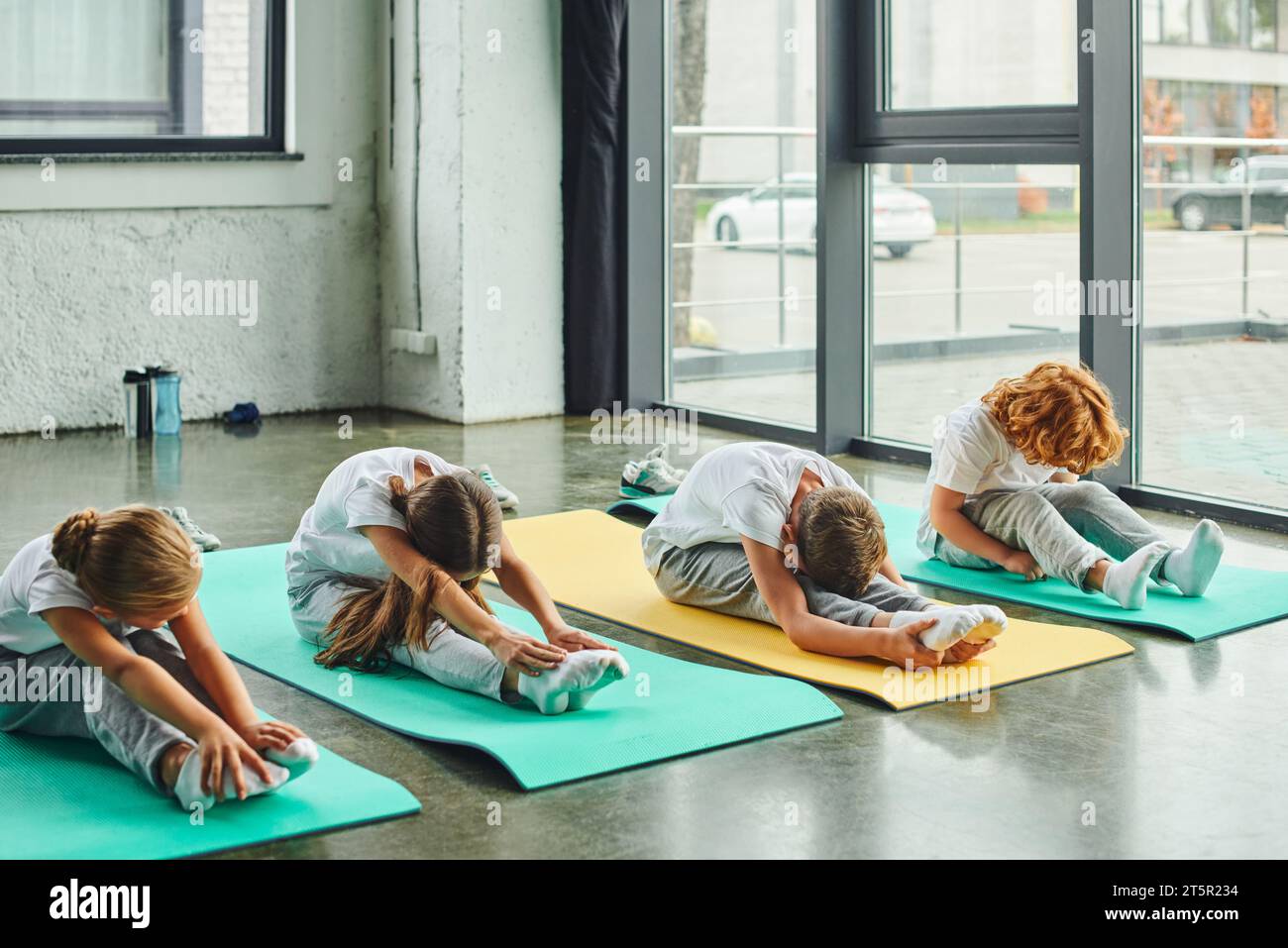 preadolescent cute boys and girls sitting on fitness mats and ...