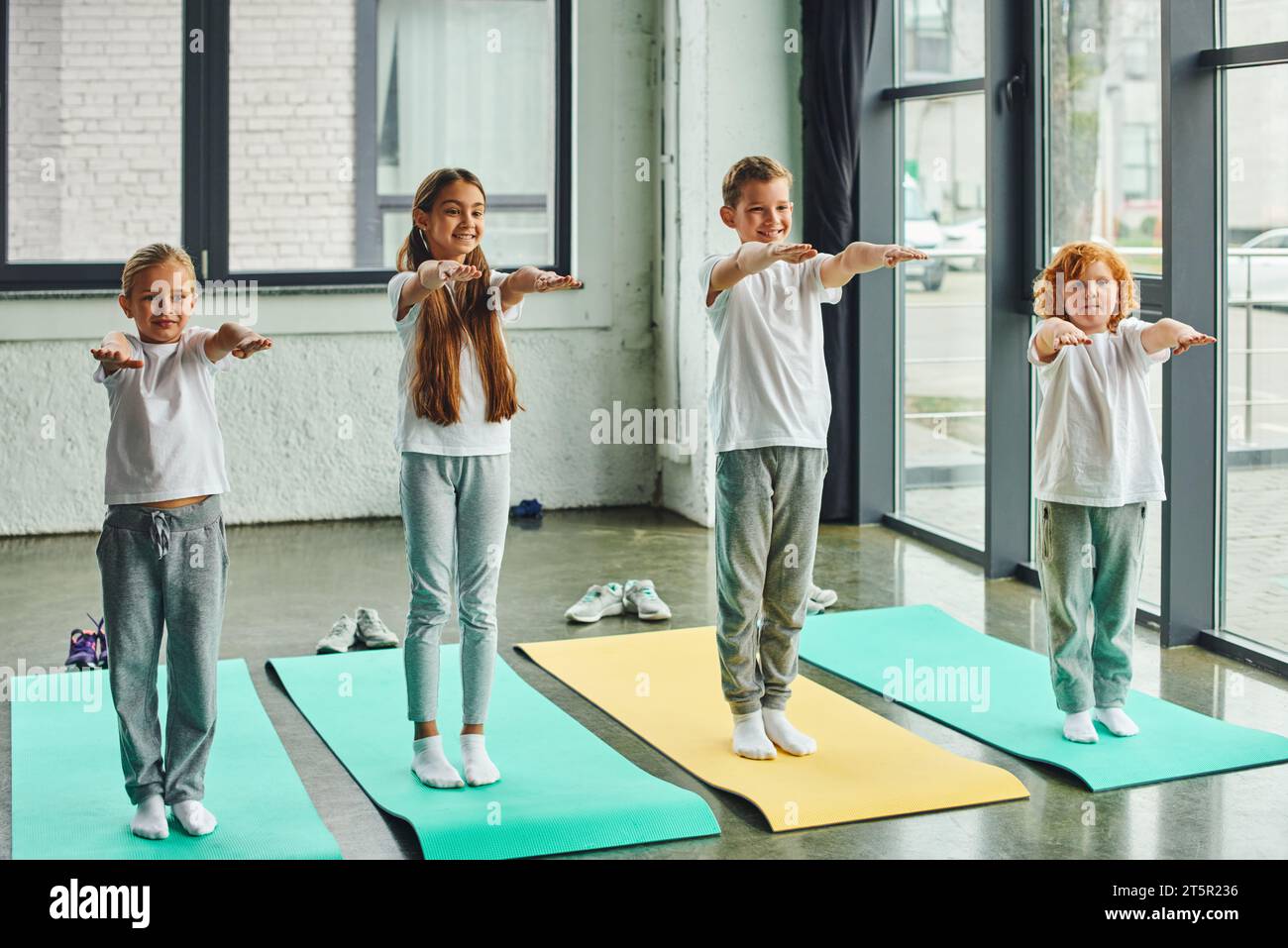 happy smiling little children stretching their arms standing on fitness ...