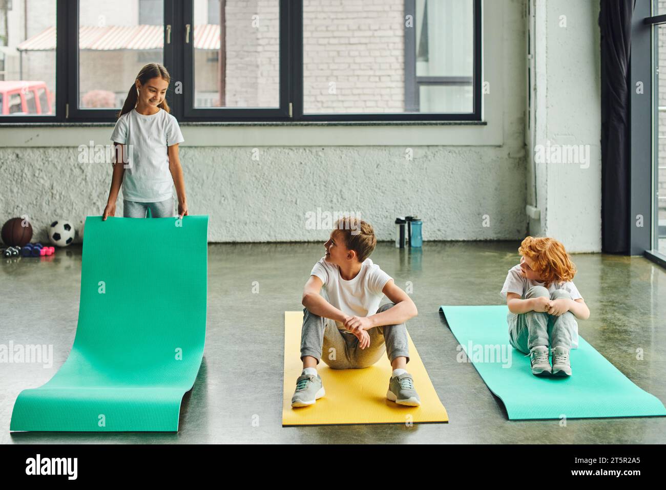two preadolescent joyful boys smiling and looking at little cute girl ...
