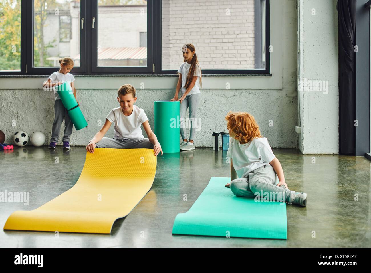 cheerful preadolescent children in sportswear unfolding fitness mats in ...