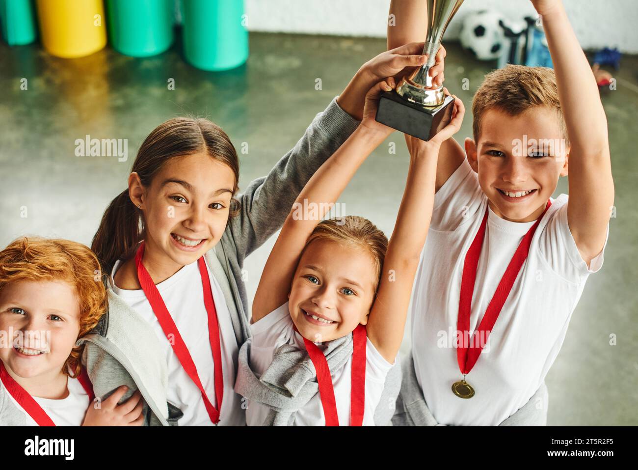 four cheerful cute preadolescent children in sportswear triumphing with ...