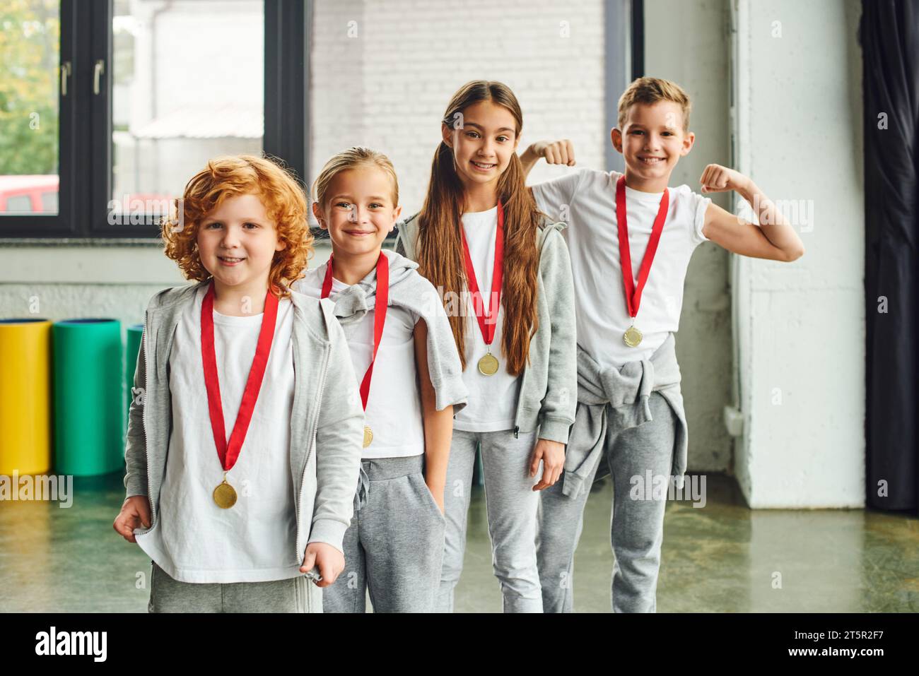 joyous children in sportswear with golden medals smiling cheerfully at ...