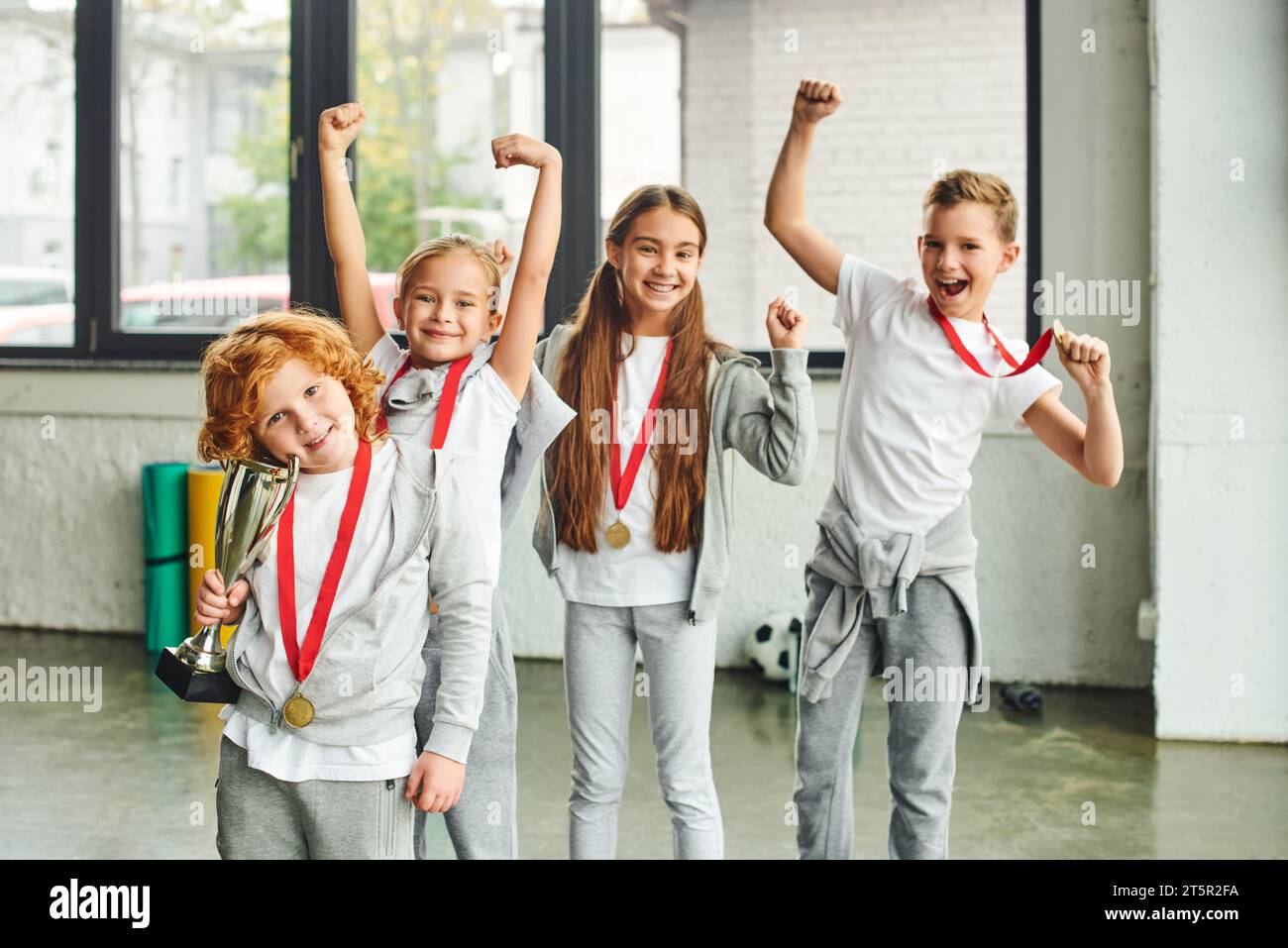 cheering boys and girls in sportswear posing happily with trophy and ...