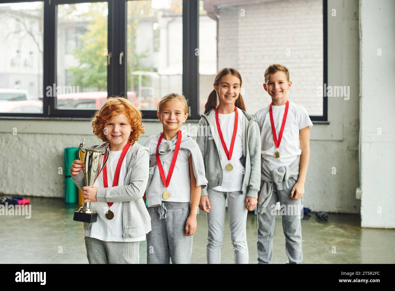 cheerful little girls and boys smiling and posing with trophy and ...
