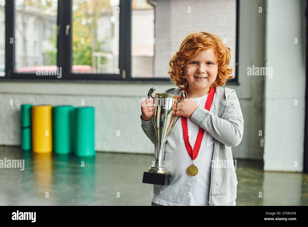 pretty red haired boy with golden medal holding huge trophy and smiling ...