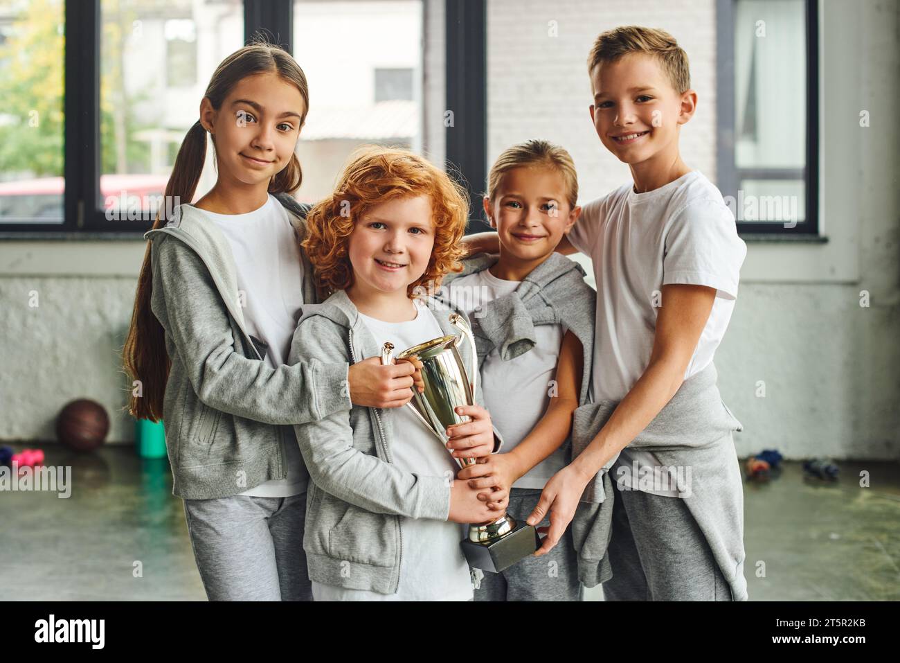 four joyous preadolescent children in grey sportswear posing with ...