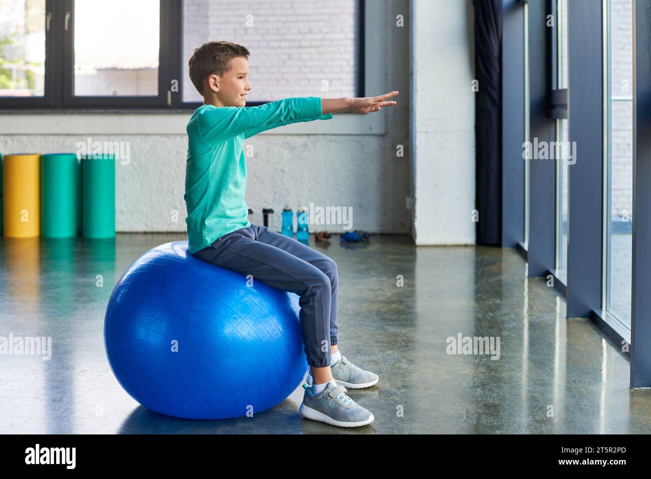 cute preadolescent boy in blue sportswear stretching and training on ...