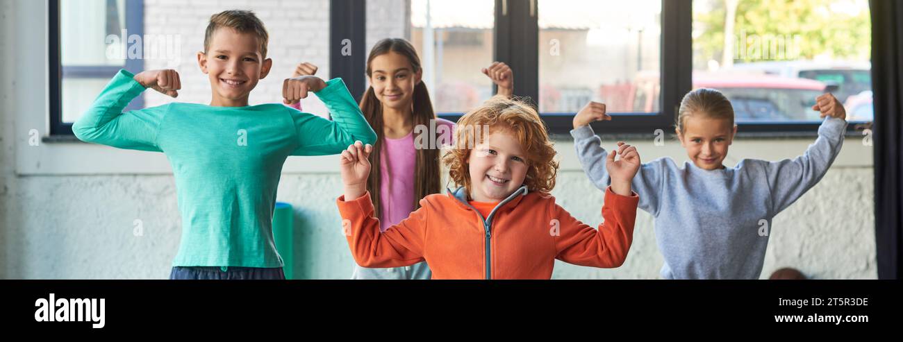 four cute little children in sportswear playing muscles and smiling at ...