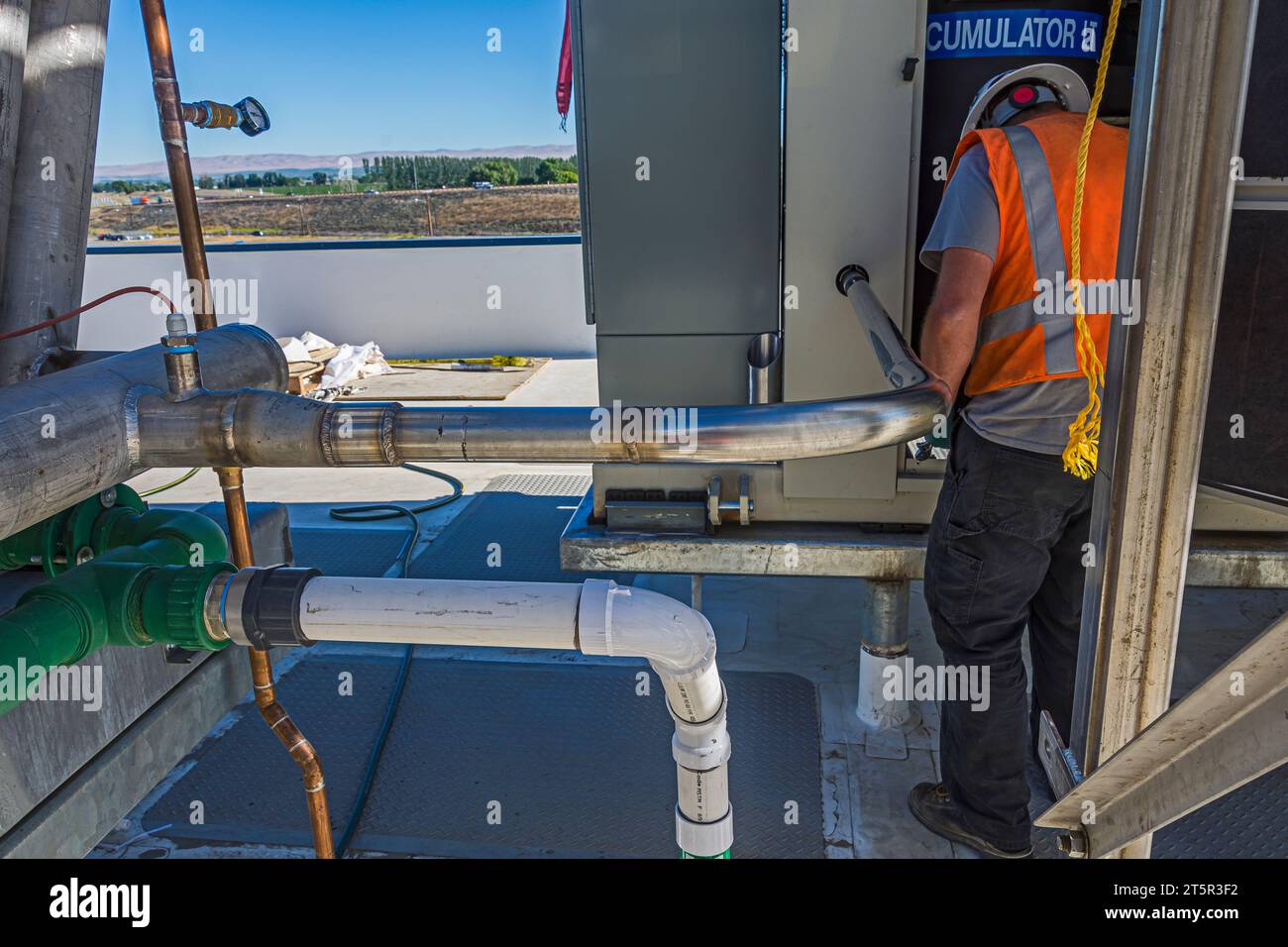 A newly welded stainless pipe and a worker working in the compressor ...
