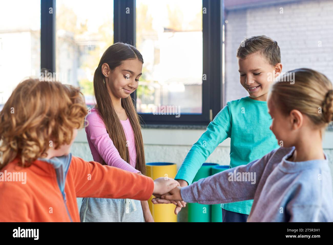 cheerful boys and girls in sportswear stacking hands together and ...