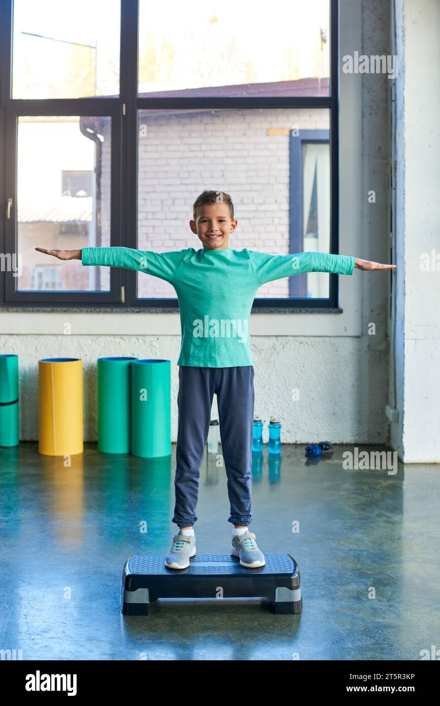 happy little cute boy standing on fitness stepper and smiling joyfully ...