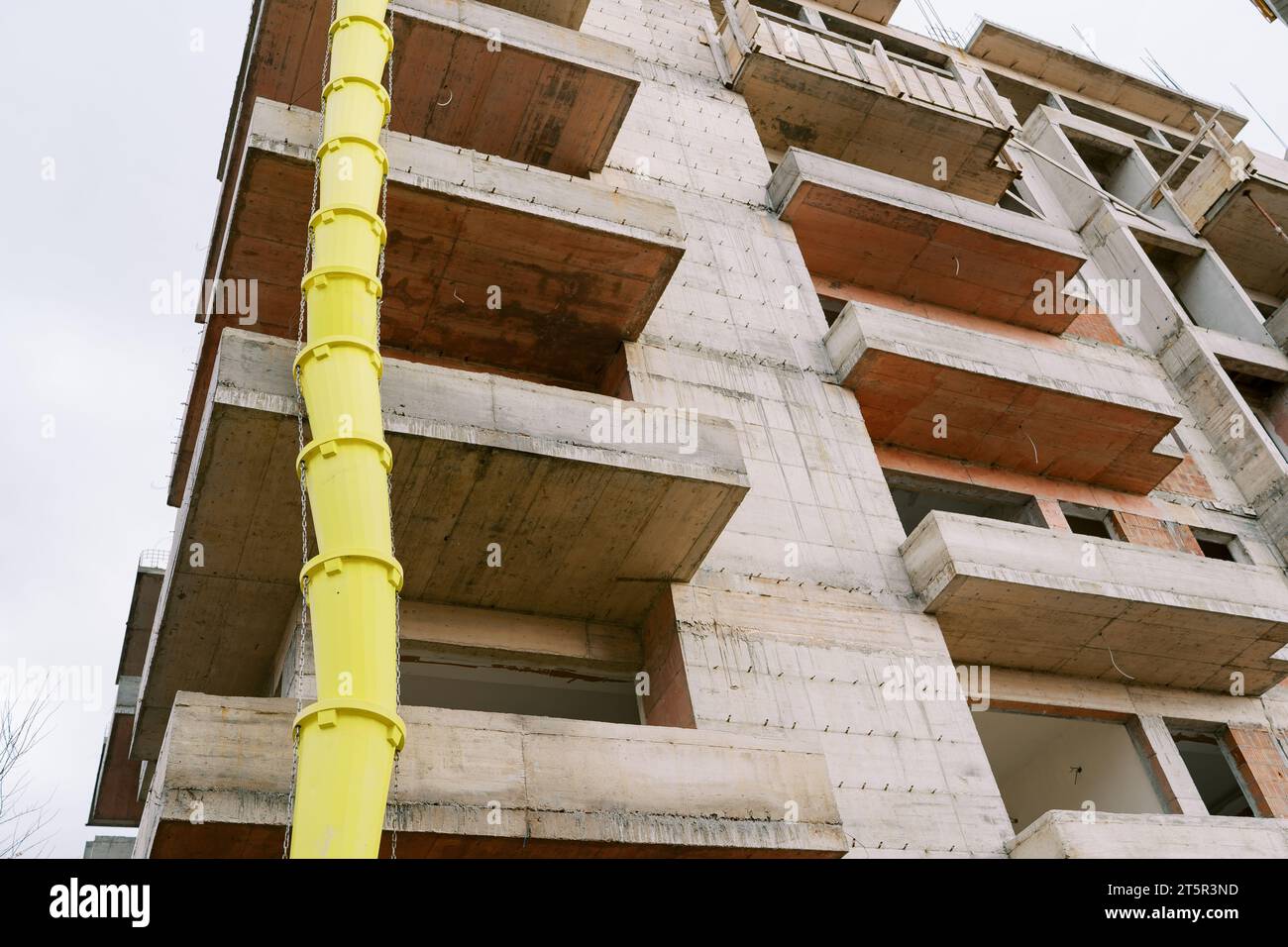 Yellow garbage pipe is attached to the outer wall of a multi-storey ...