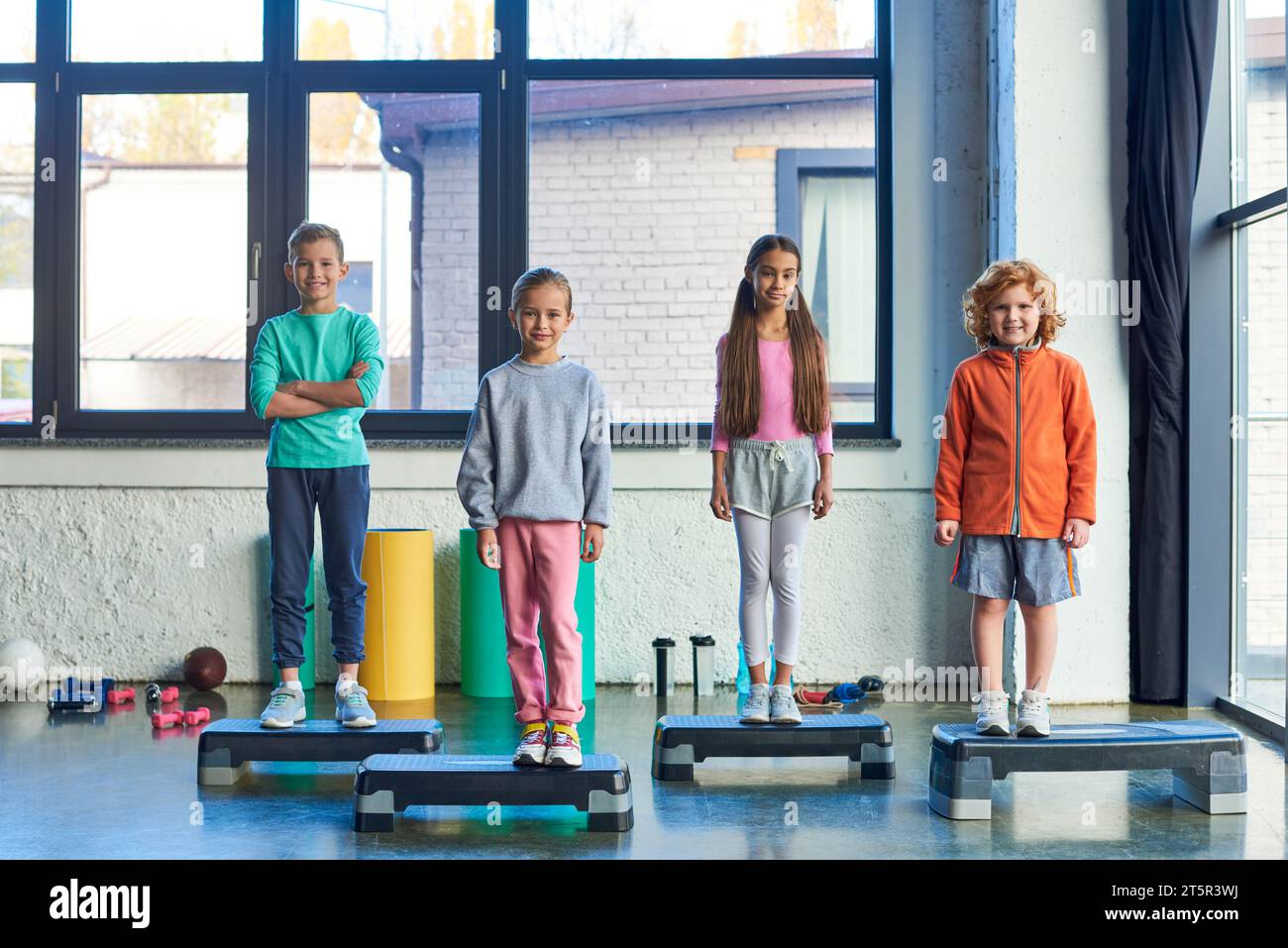 cute preadolescent children standing on fitness steppers and smiling at ...