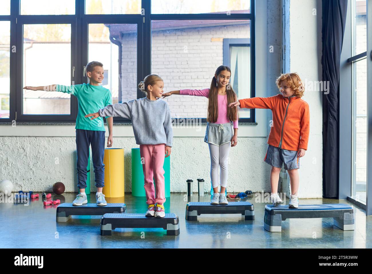 four little cute children in sportswear stretching arms standing ...