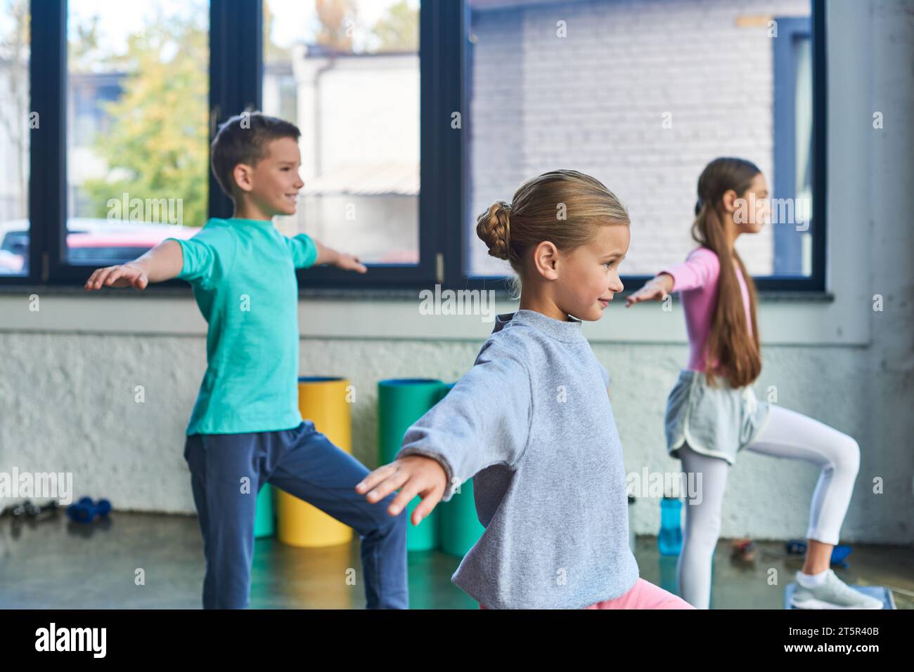 cheerful three kids in sportswear doing exercises stretching with hands ...