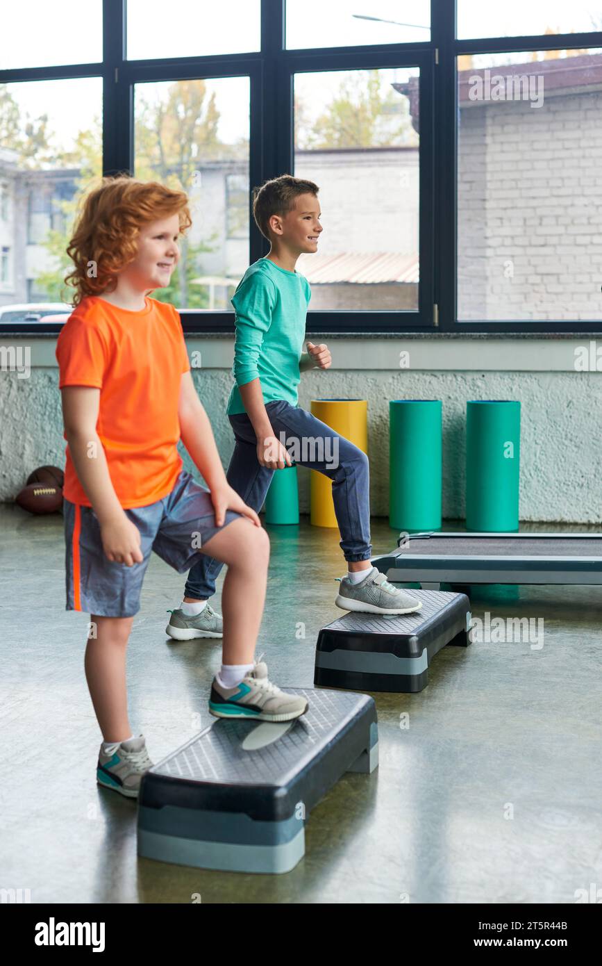 vertical shot of cute little boys in sportswear exercising on fitness ...