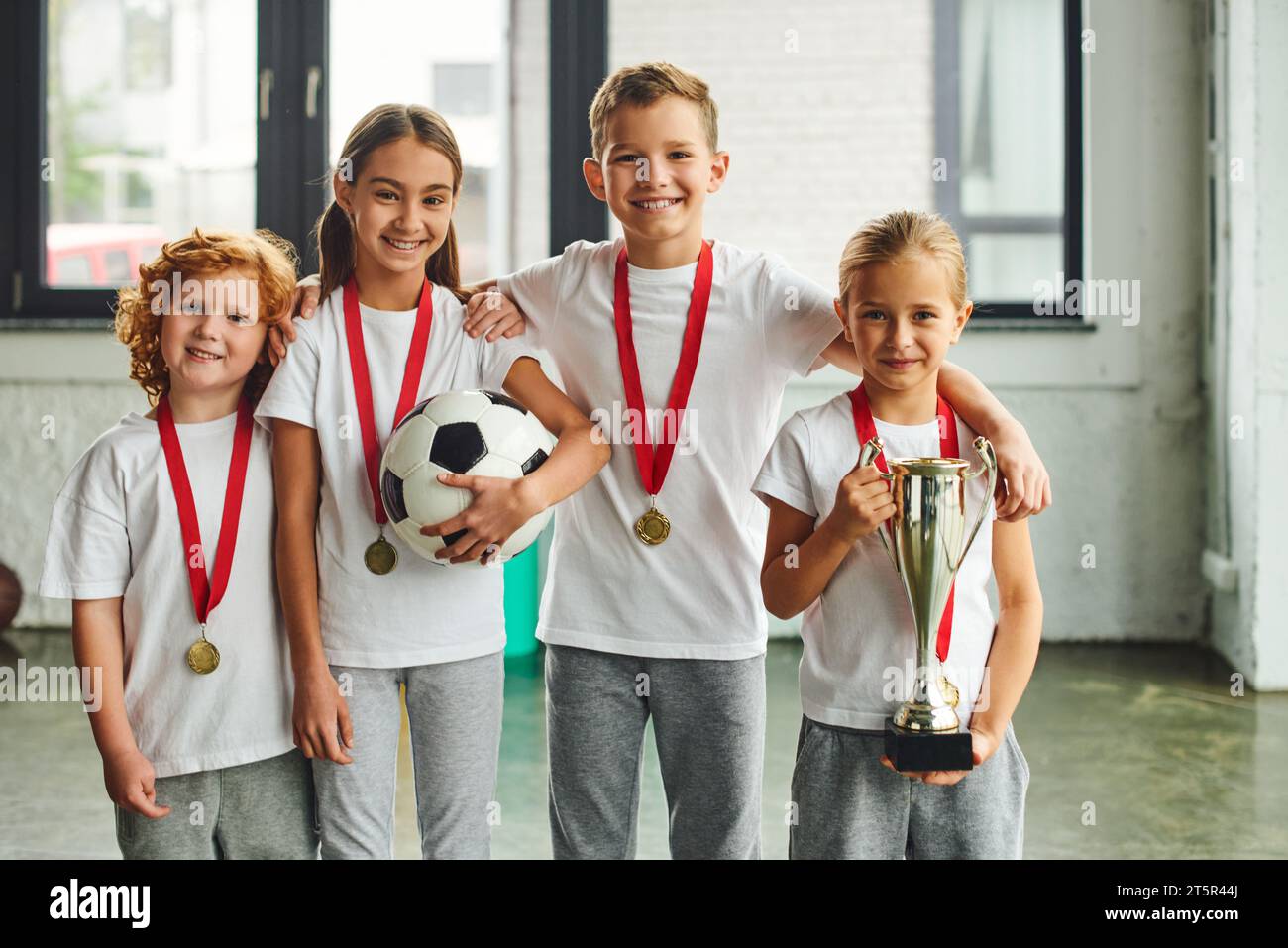 joyous little boys and girls with medals smiling at camera and holding ...