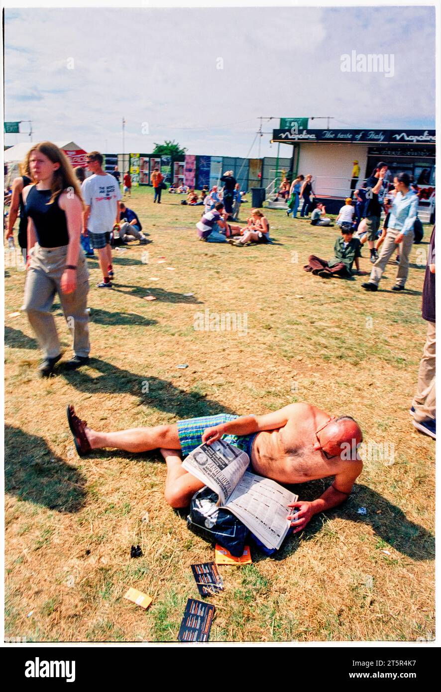 BRITPOP and ROCK FANS, READING FESTIVAL, 1998: An older fan reads a ...