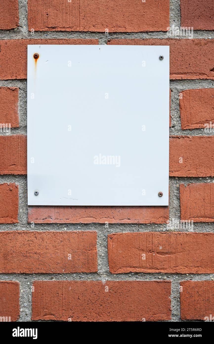 Blank white notice board attached to a brick wall with four screws ...