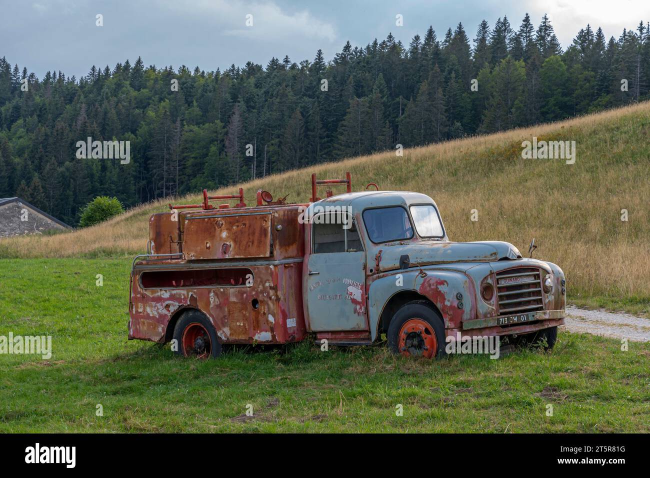 View of an old red and blue rusty fire engine and forest around Stock ...