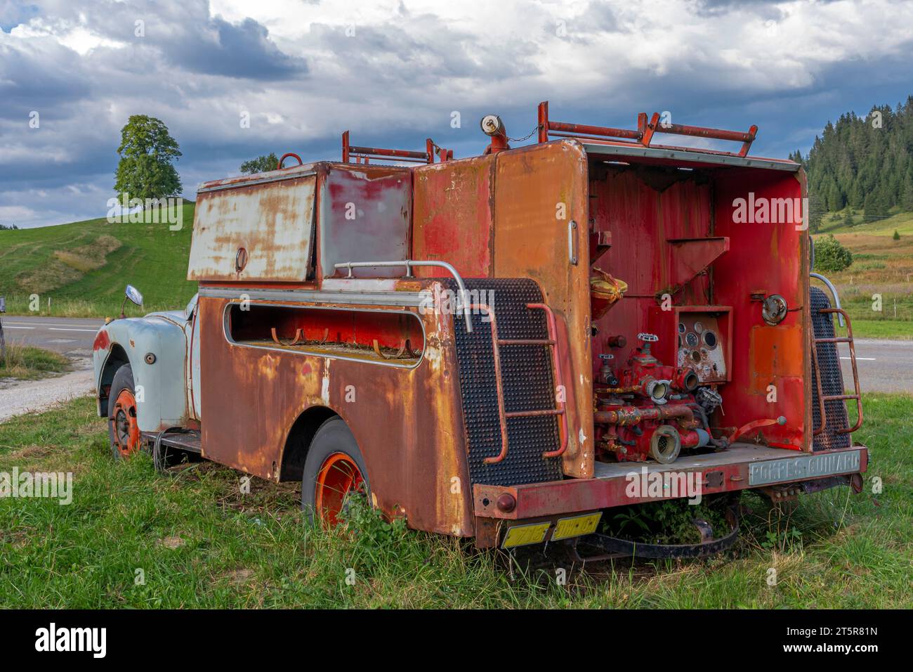 View of an old red and blue rusty fire engine and forest around Stock ...