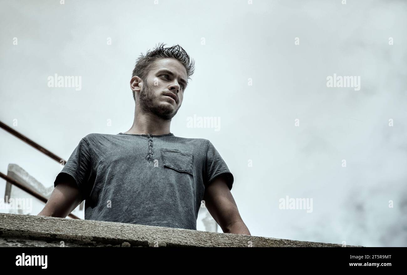 A man standing on top of a cement wall. Photo of a man standing ...